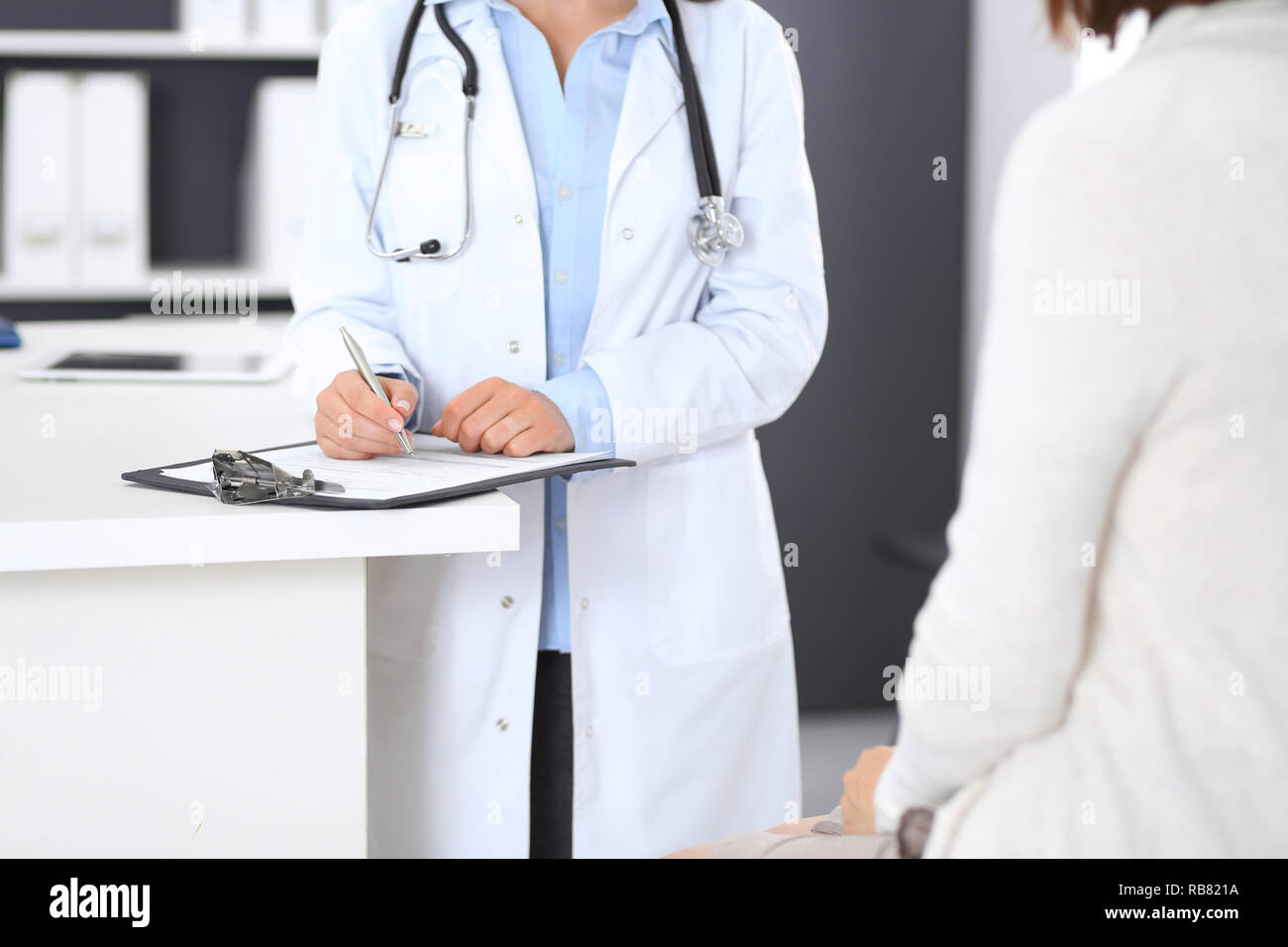 Unknown doctor and female patient discussing something while standing ...