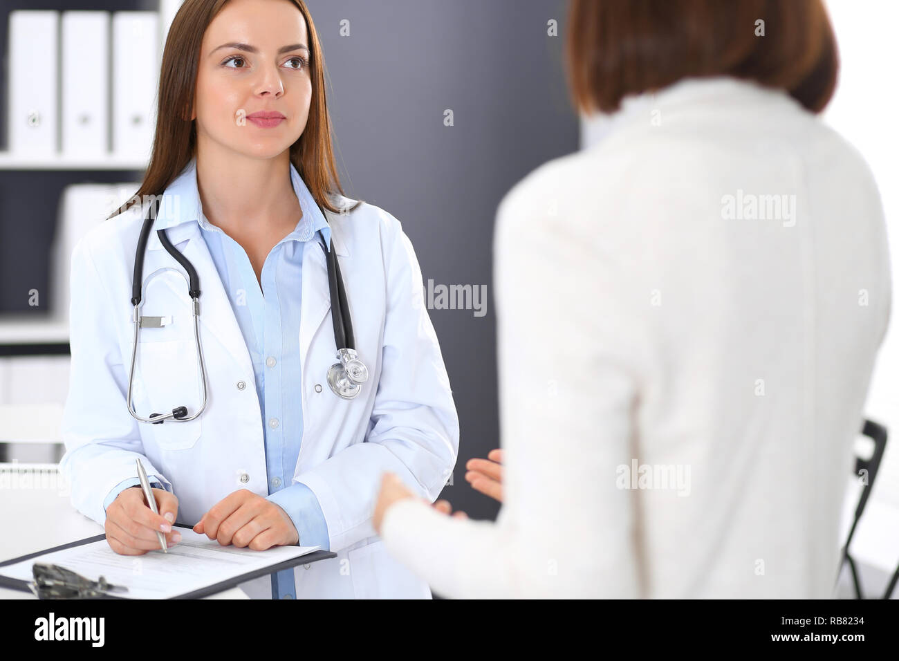 Doctor and patient discussing something while standing near reception ...