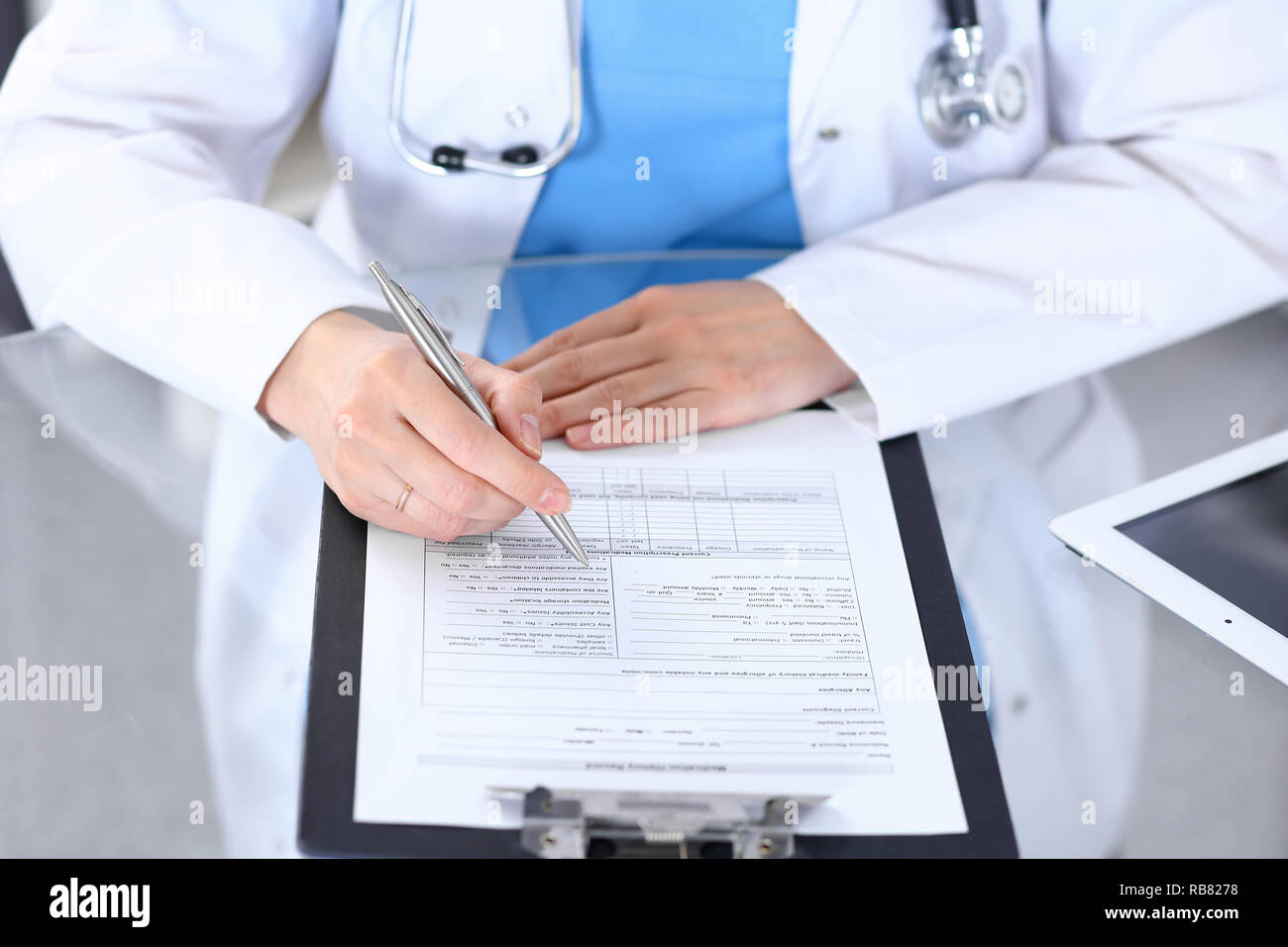 Female doctor filling up medical form on a clipboard, closeup ...