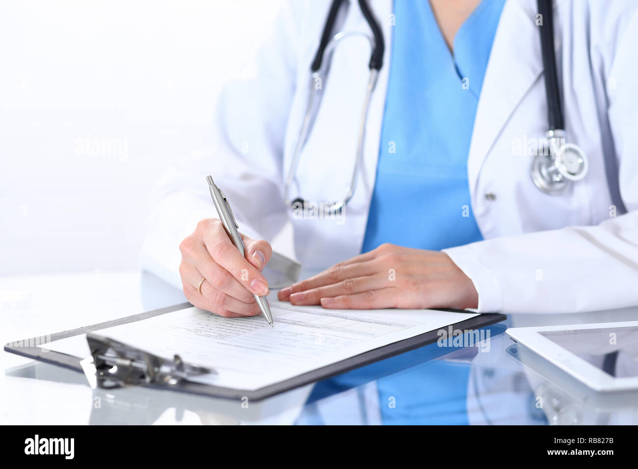 Female doctor filling up medical form on a clipboard, closeup ...