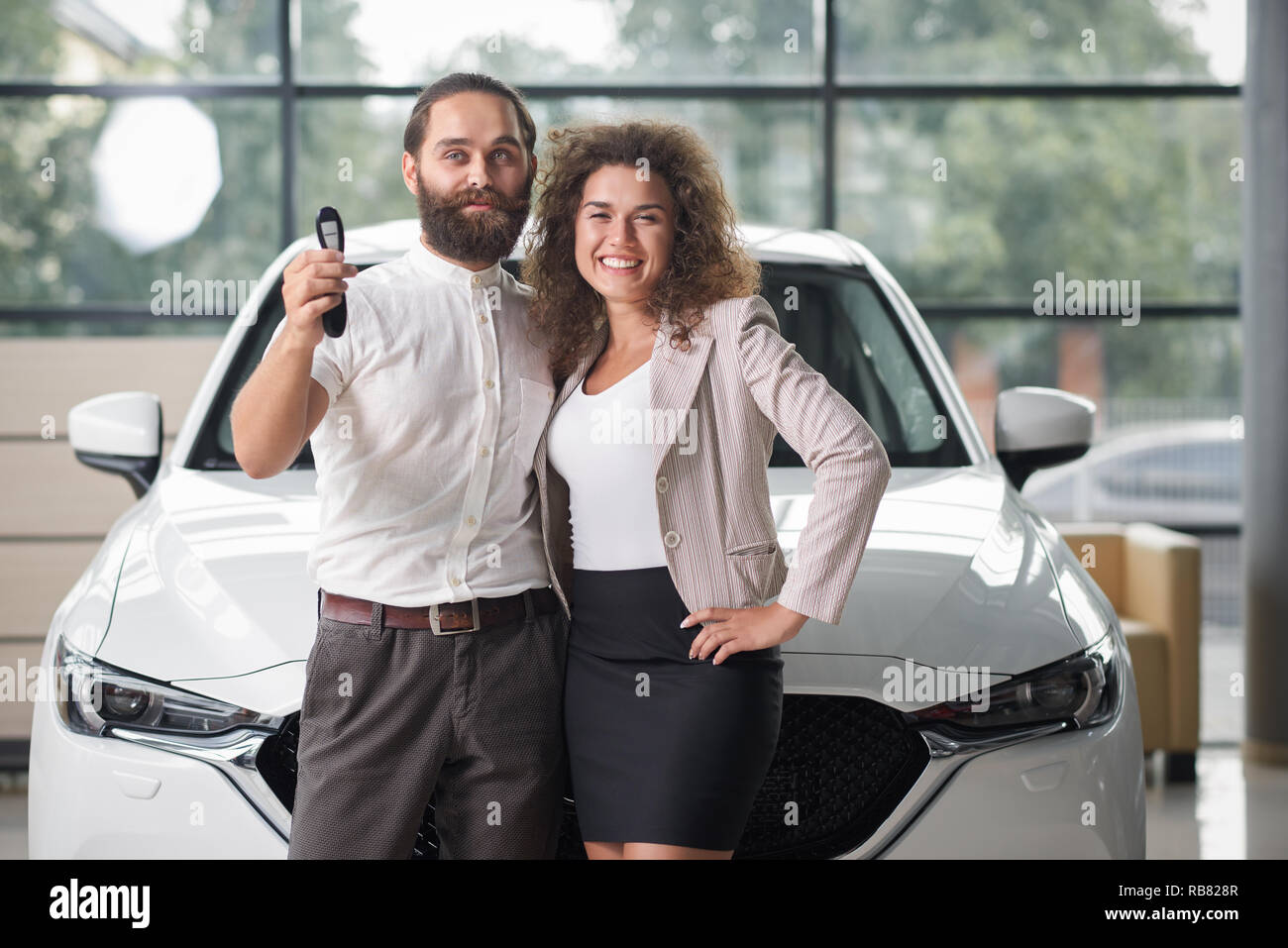 Smiling husband and wife standing near new expensive automobile in car ...