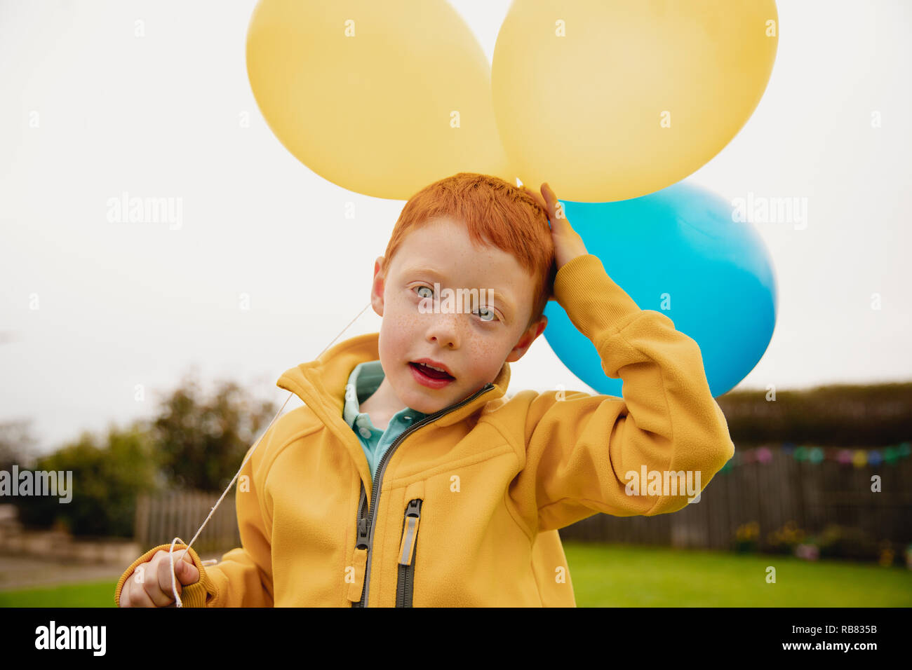 Headshot of a little boy looking at the camera while holding two yellow ...