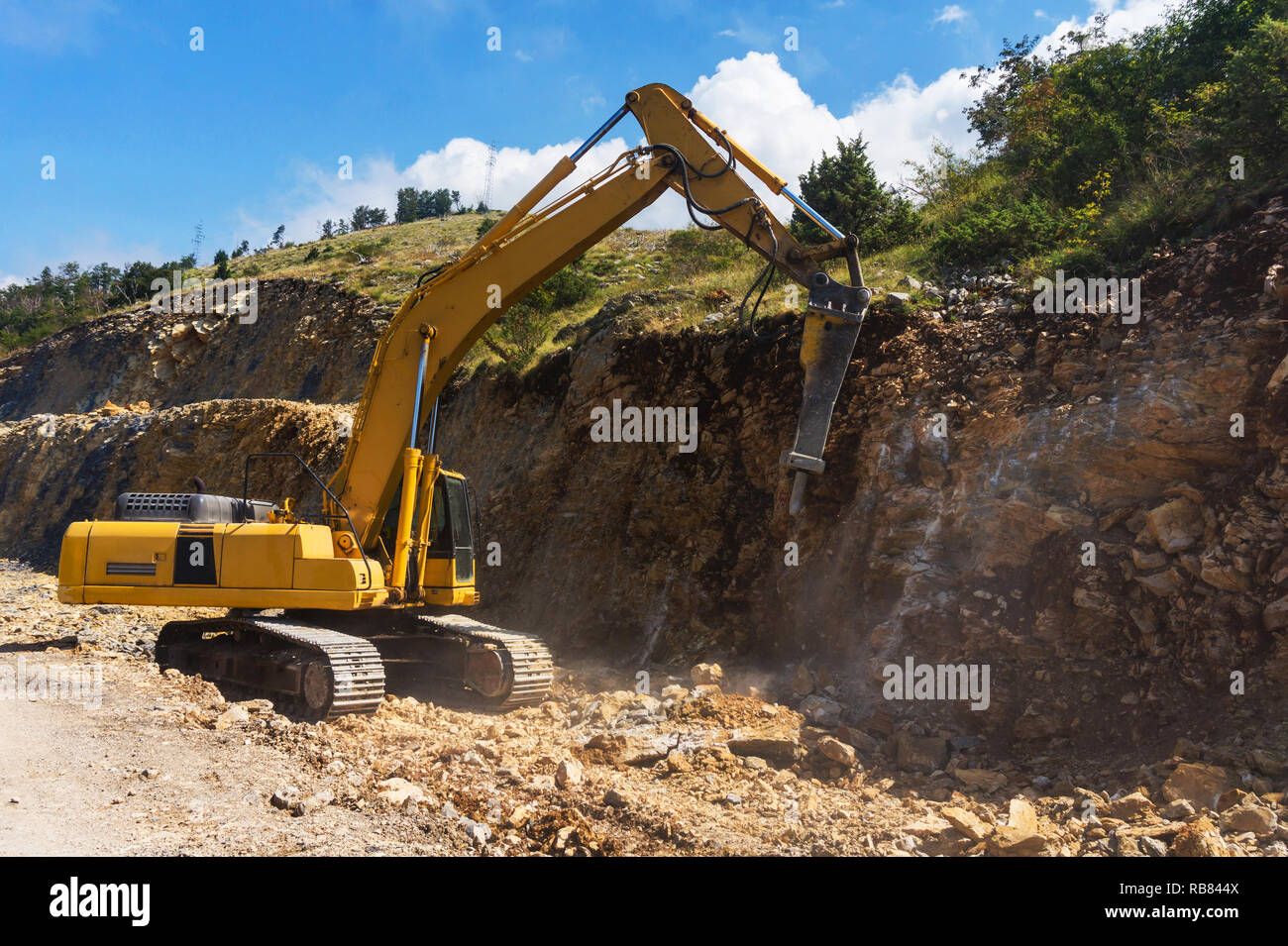 Excavator with hydraulic breaker destroys rock in road construction ...