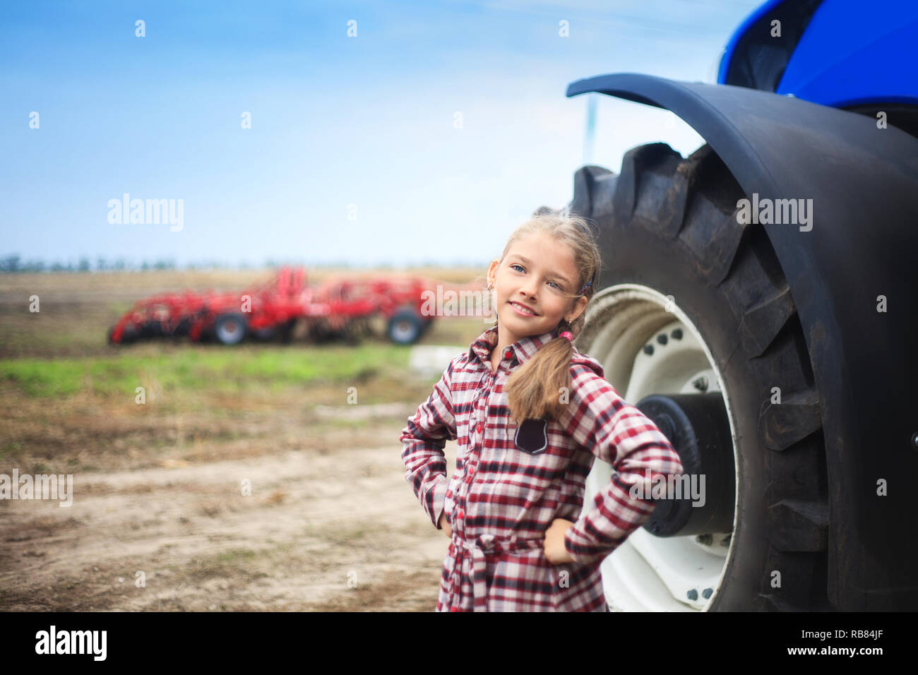 Cute girl near the modern tractor in the field. The concept of field ...