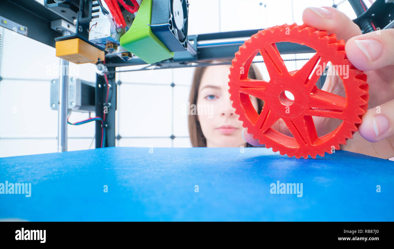 Young women designer in 3d printing lab. Girl takes the finished detail ...