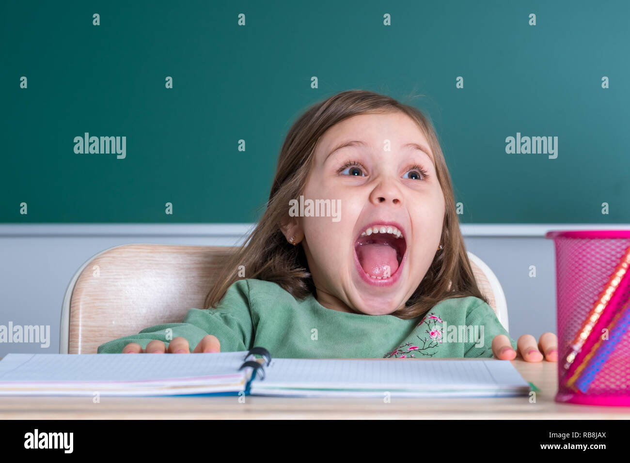 Little pretty girl sitting in the classroom at the gray desk and posing ...