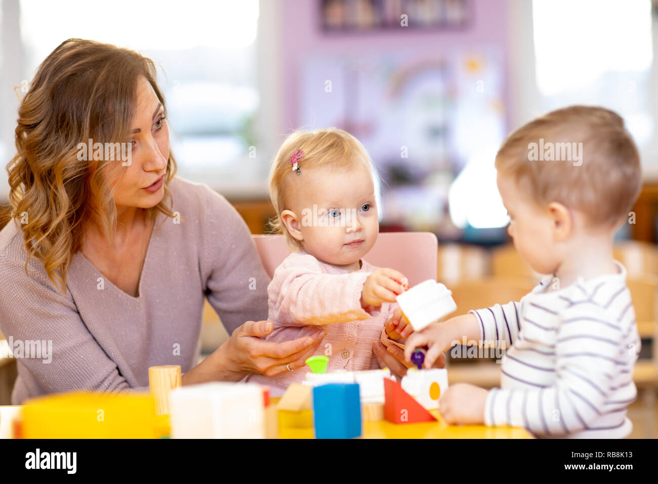 Nursery children playing with teacher in the class room Stock Photo - Alamy