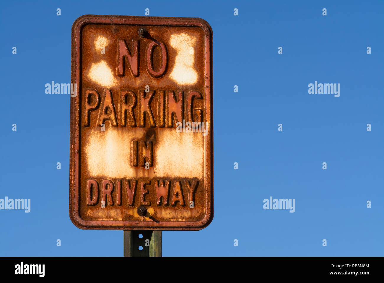 Rusty "No Parking in Driveway" street sign in the afternoon light Stock ...