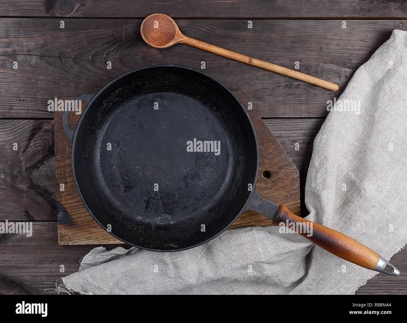 empty black round pan with wooden handle and wooden spoon on a brown ...