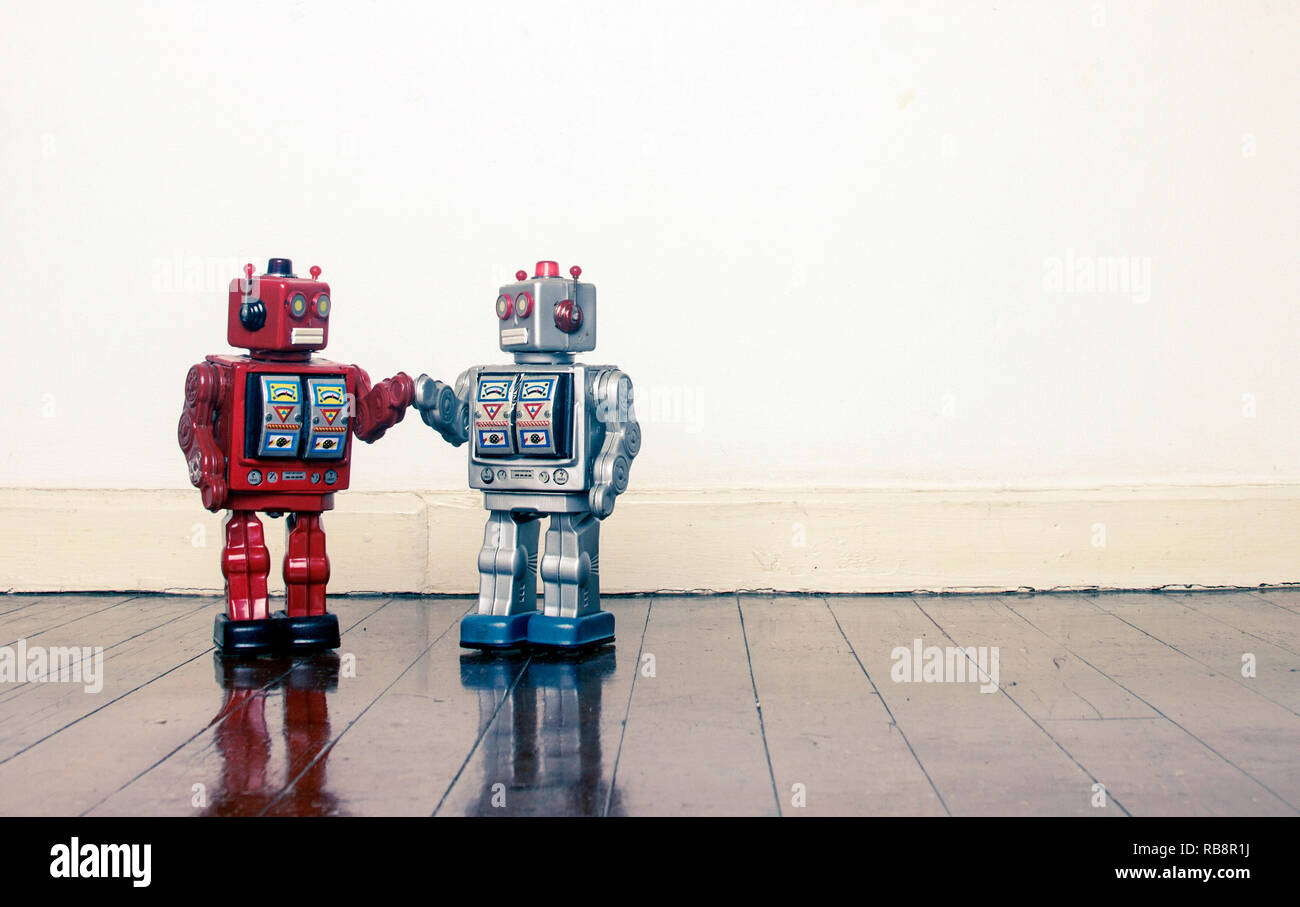 big red and silver robots holding hands with love on an old wooden ...