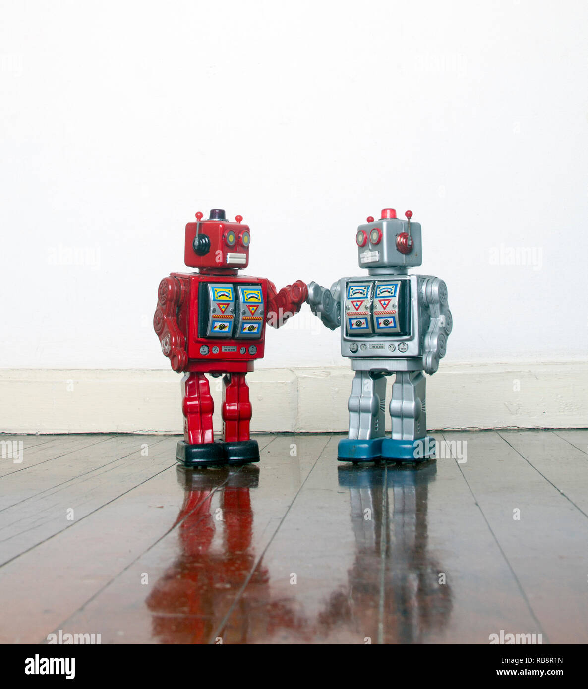 big red and silver robots holding hands with love on an old wooden ...