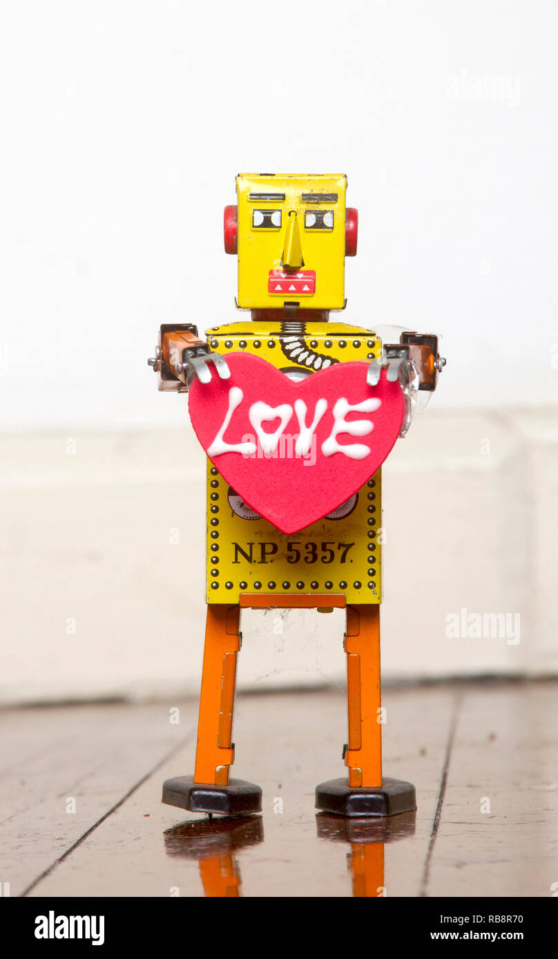 retro yellow robot toy holding a red heart with love Stock Photo - Alamy