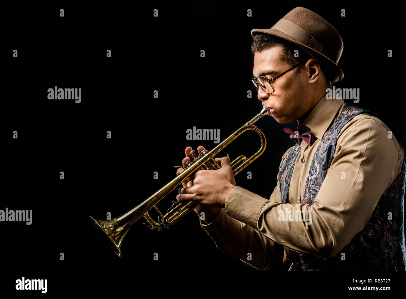 side view of mixed race male jazzman in hat and eyeglasses playing on ...