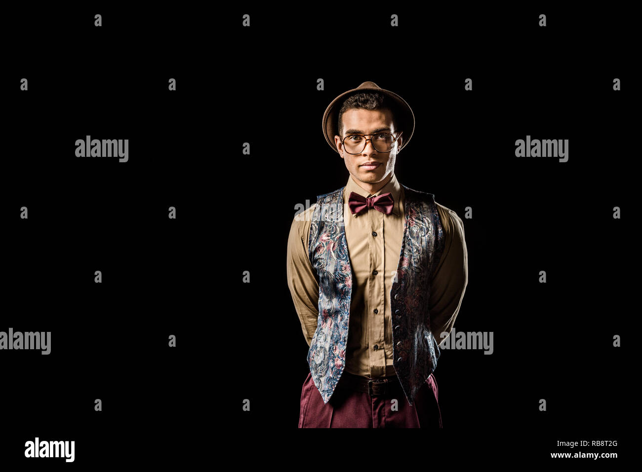 stylish young male model in vest and bow tie posing isolated on black ...