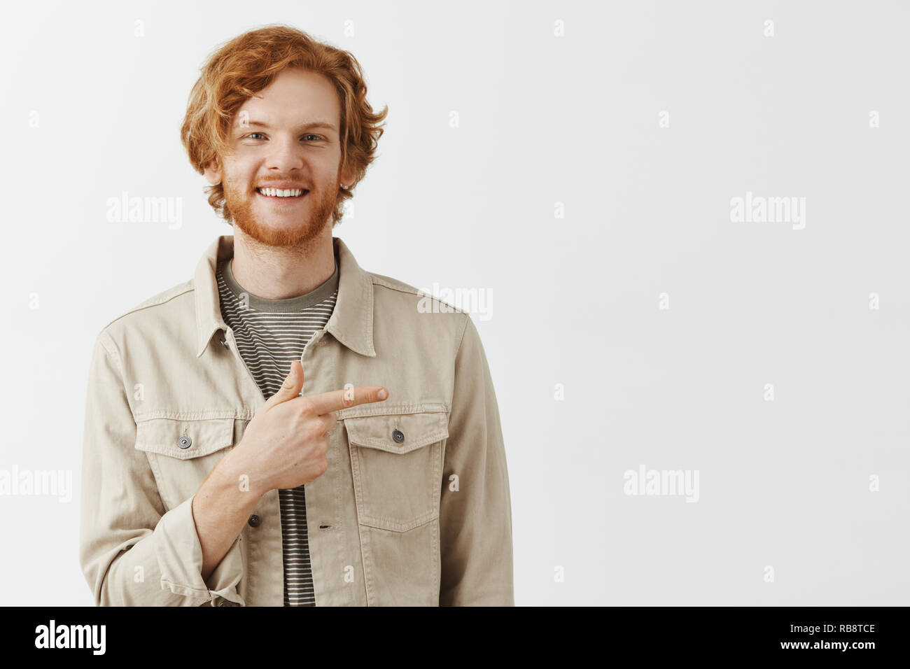 Kind and handsome ginger man with beard and wavy hair in outdoor street ...