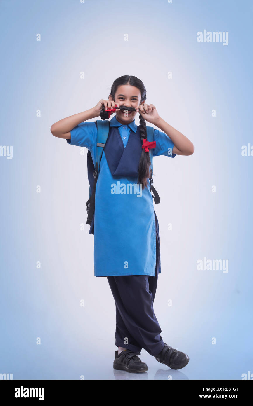 Playful school girl making a mustache with her hair against a blue ...