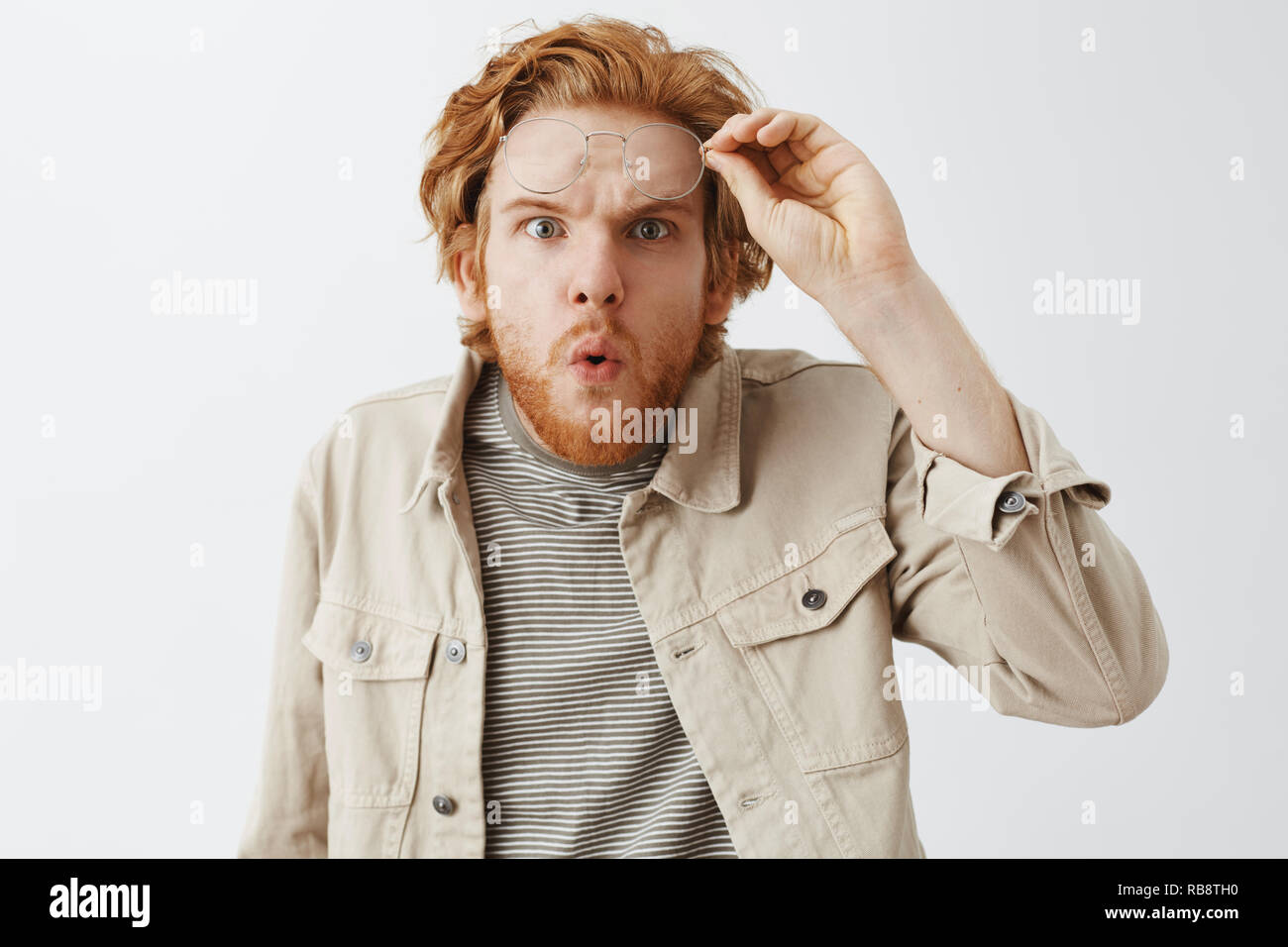 Waist-up shot of shocked questioned and impressed redhead guy seeing ...