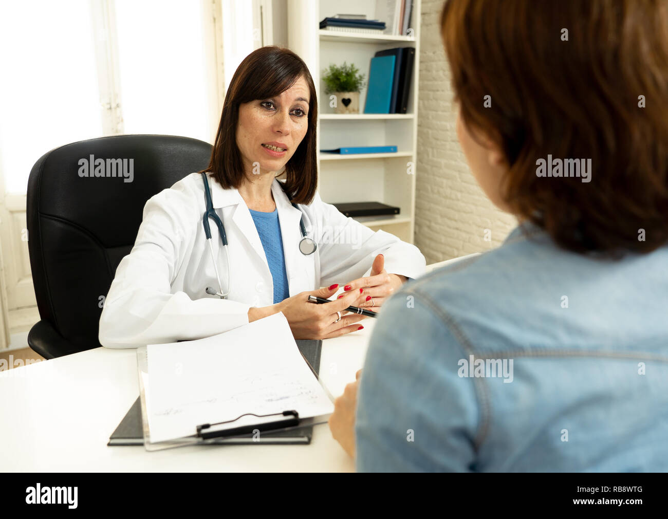 Female family doctor listening carefully with sympathy to woman patient ...