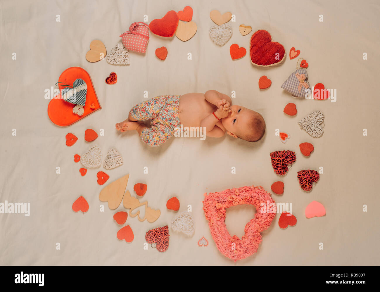 Maternal warmth. Small girl among red hearts. Love. Portrait of happy ...