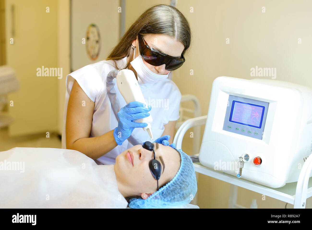 Young cosmetologist removing permanent makeup with laser for young girl ...