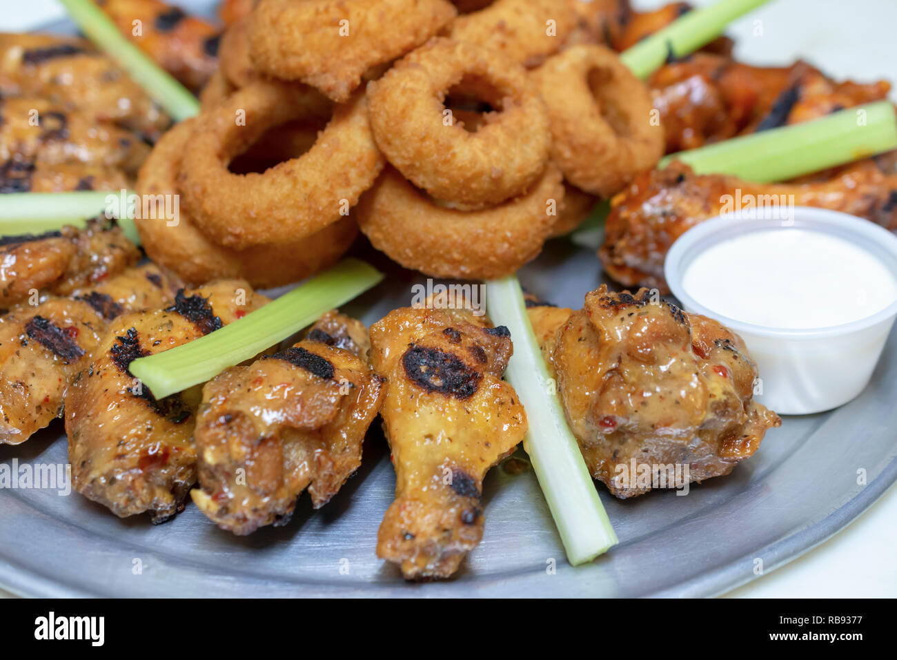 Bar Food: Chicken wing plate with onion rings and celery. Close up view ...