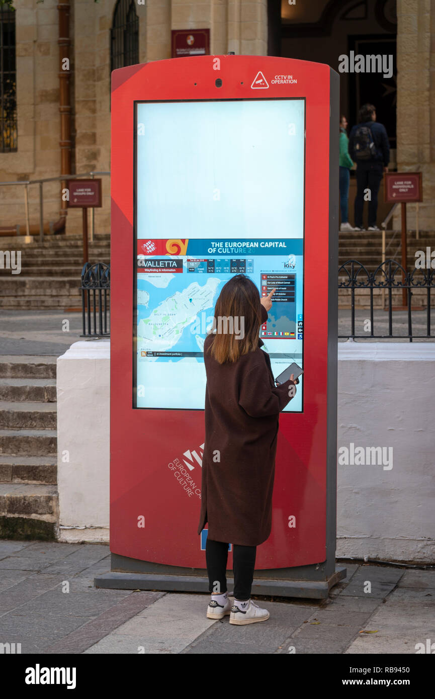 woman tourist using a touch screen tourist information display in ...