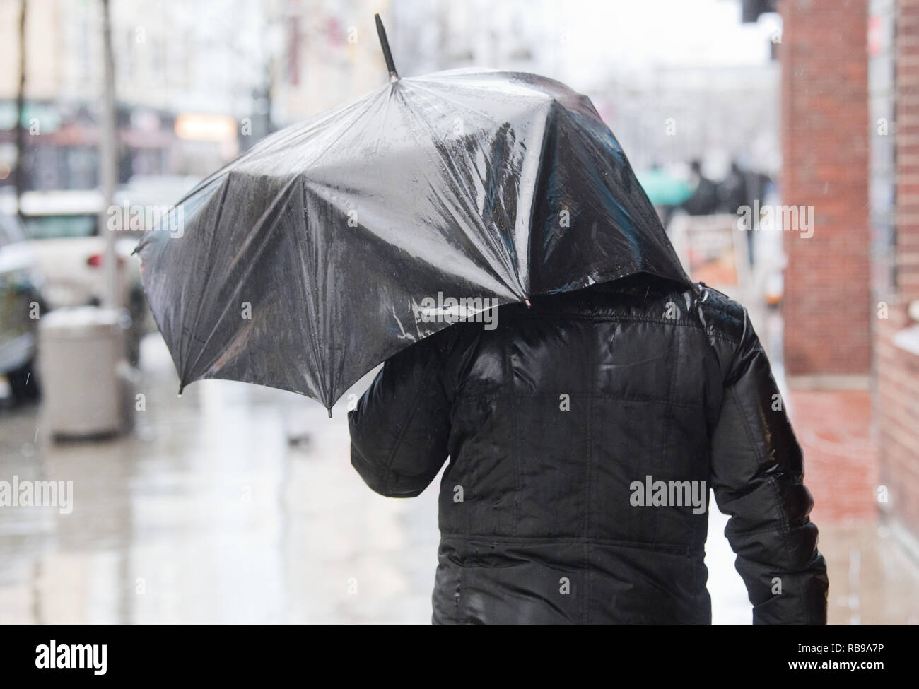 Hannover, Germany. 08th Jan, 2019. A walker with an umbrella is caught ...