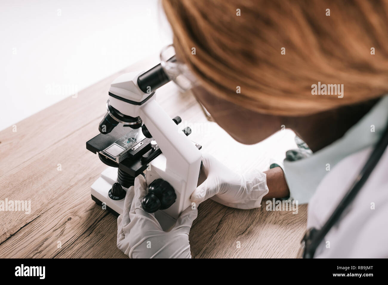 cropped view of female african american scientist looking through ...