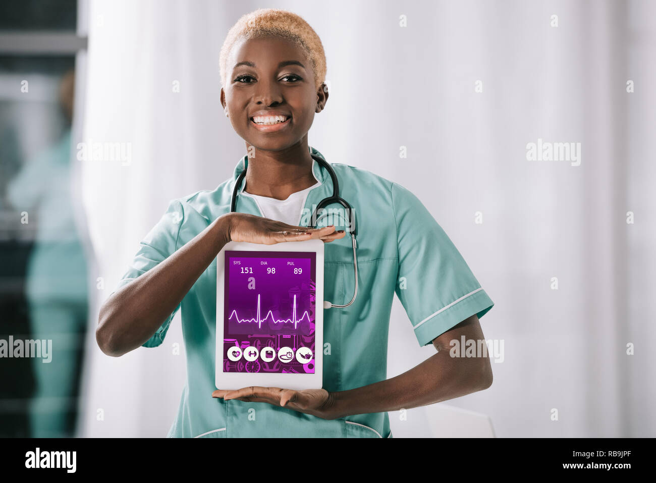 cheerful african american nurse with stethoscope holding digital tablet ...