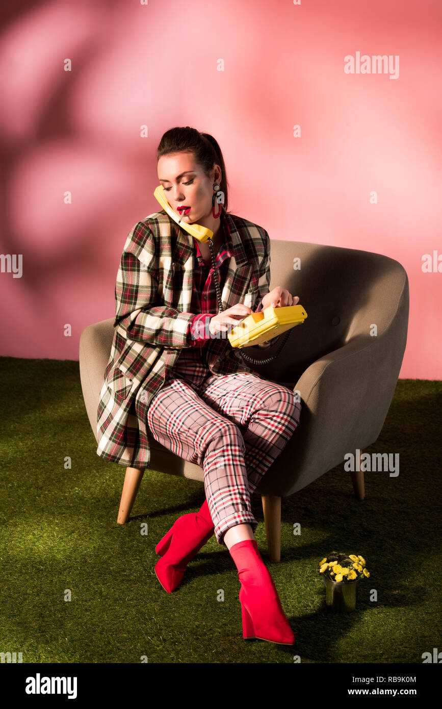 fashionable girl in armchair smoking cigarette while talking on retro ...