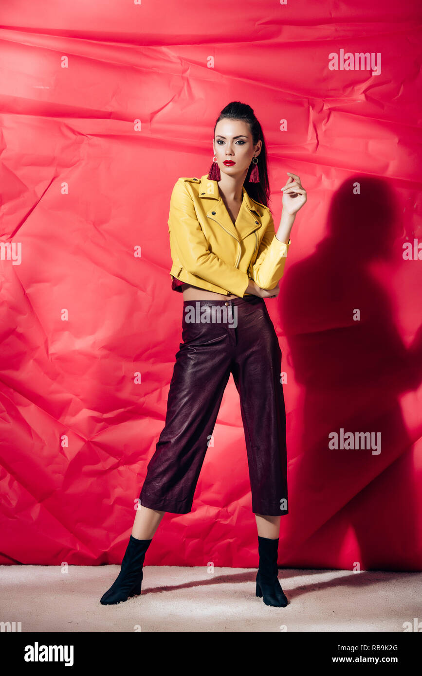fashionable brunette model posing in yellow leather jacket on red ...