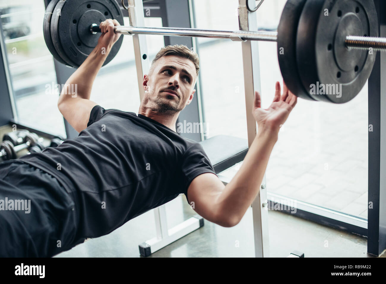 handsome sportsman lying on bench to lift barbell in gym Stock Photo ...