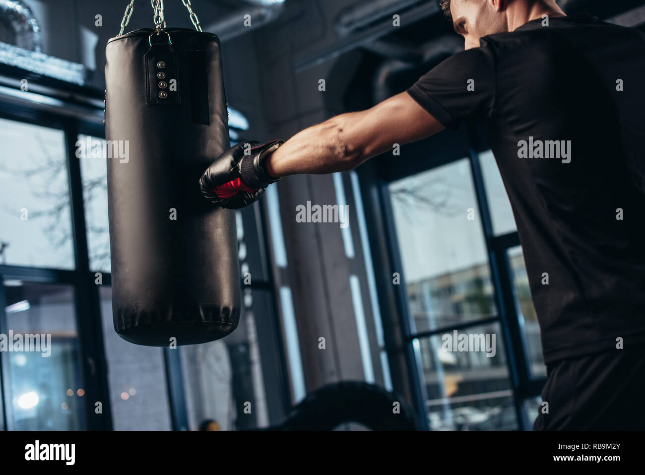 side view of handsome boxer training with punching bag in gym Stock ...