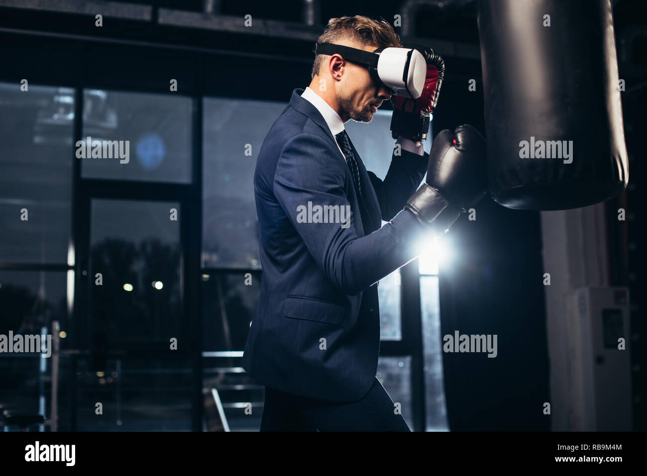 side view of businessman in suit and virtual reality headset boxing in ...
