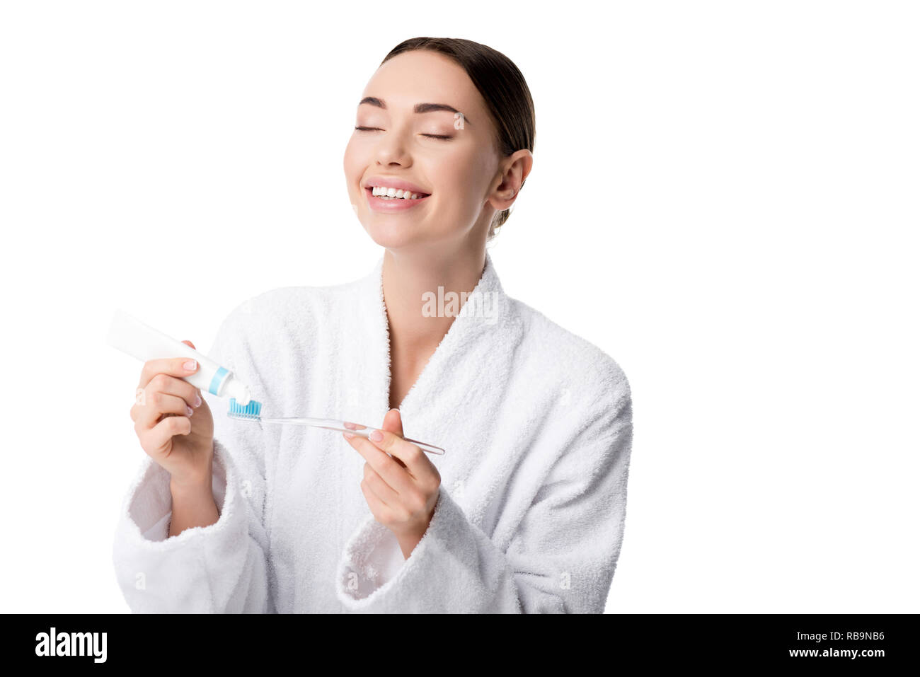 beautiful happy woman in white bathrobe putting toothpaste on ...