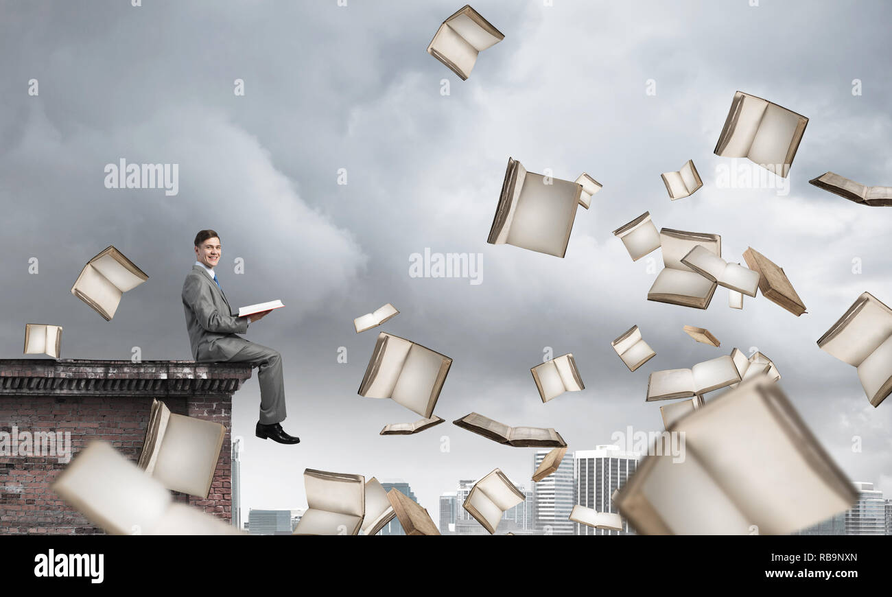 Man on roof reading book and many of them flying in air Stock Photo - Alamy