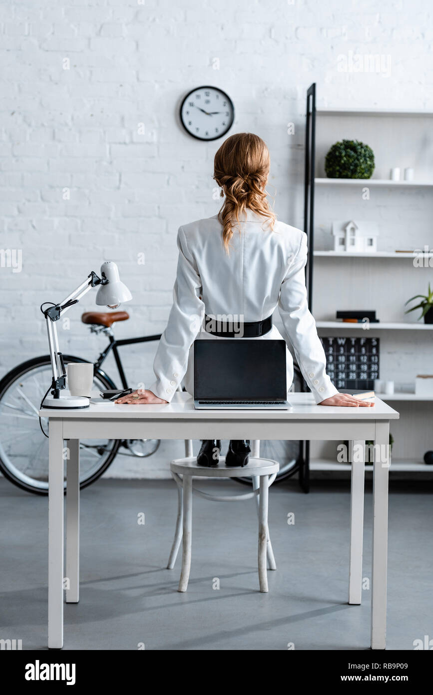 back view of businesswoman in formal wear sitting on computer desk in ...