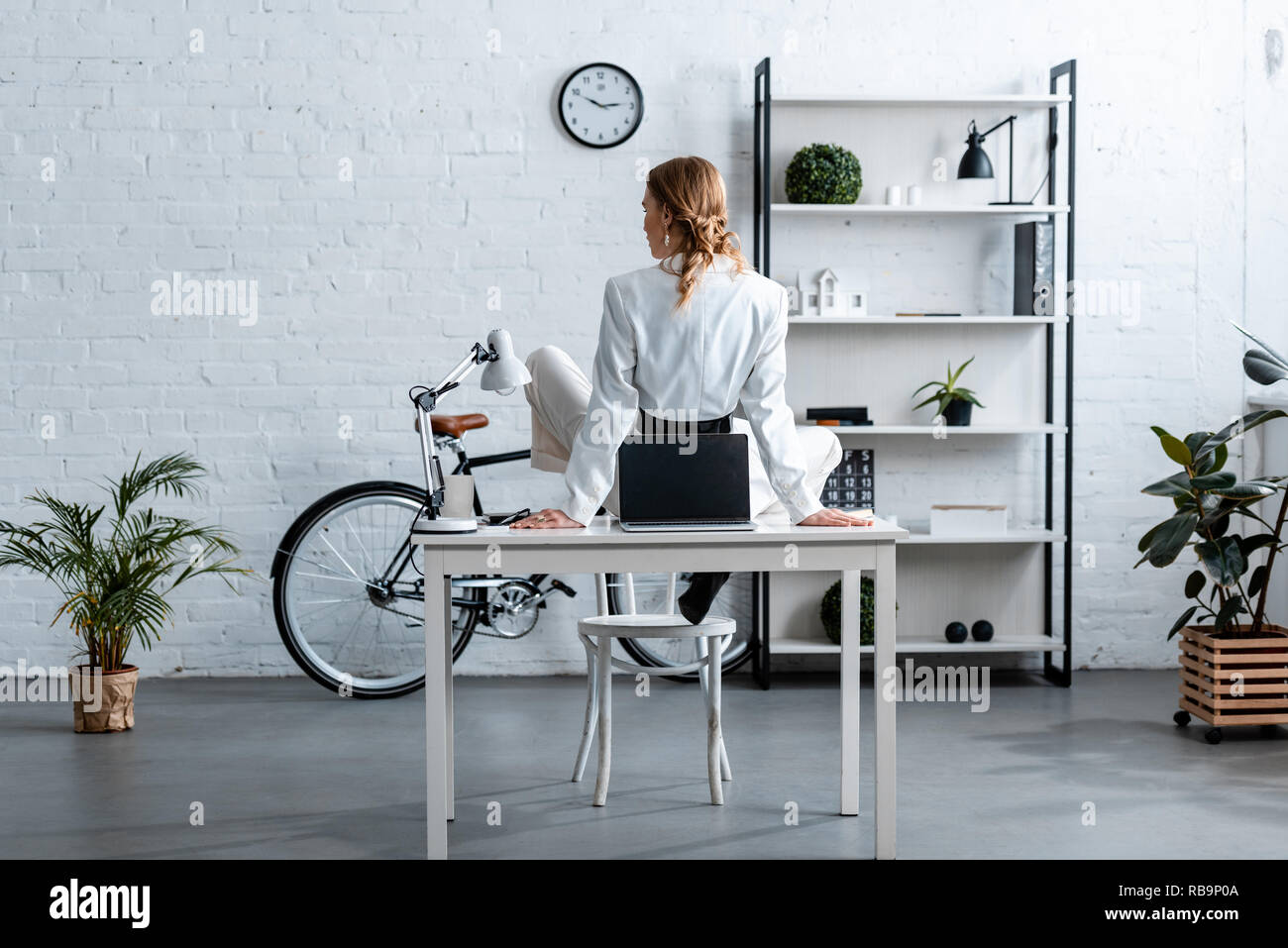 back view of businesswoman in formal wear sitting on computer desk in ...