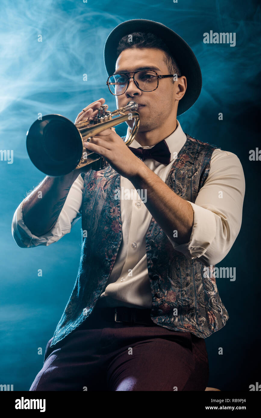 confident young jazzman playing on trumpet on stage with dramatic ...