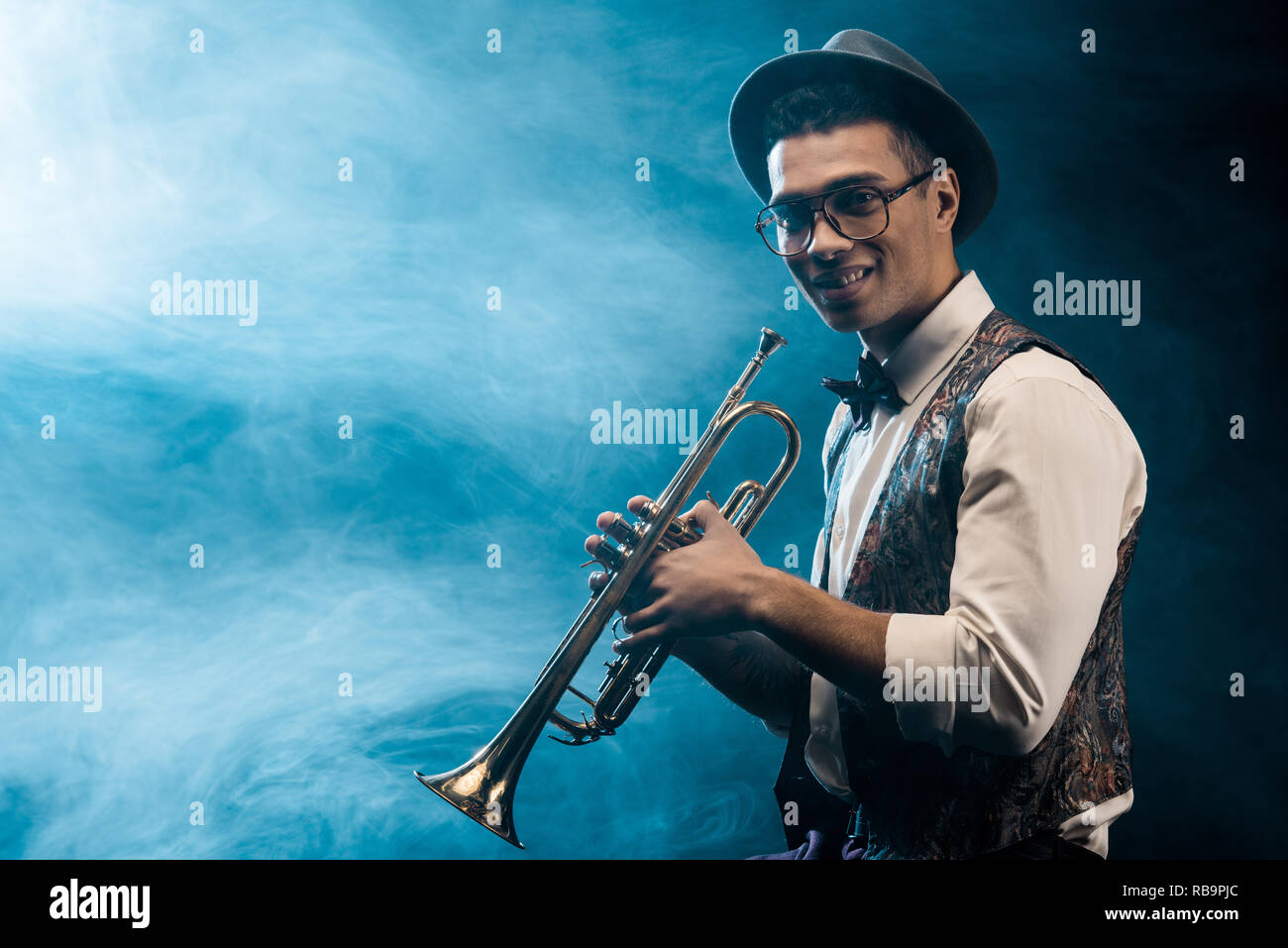 smiling male musician posing with trumpet on stage with dramatic ...