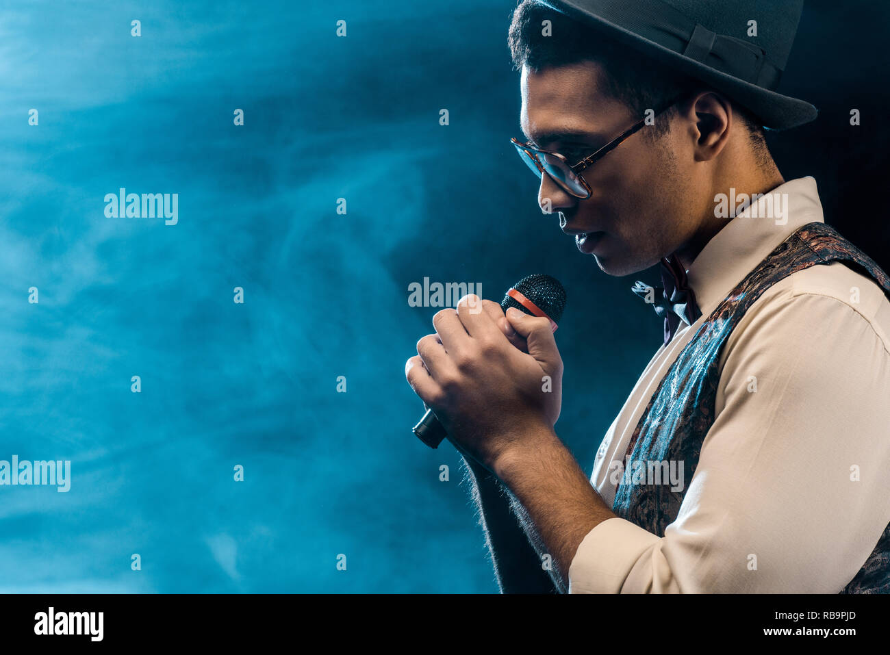 side view of handsome stylish man singing in microphone on stage with ...