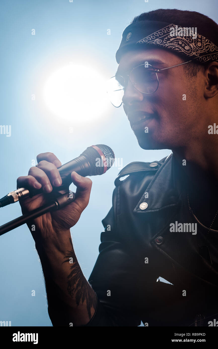 handsome male rock musician singing in microphone on stage with ...