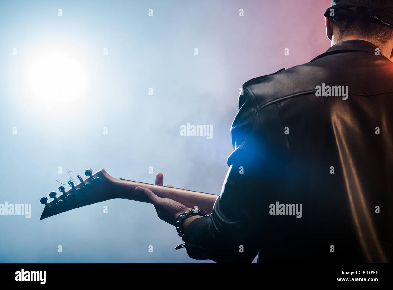 rear view of male rock star in leather jacket performing on electric ...