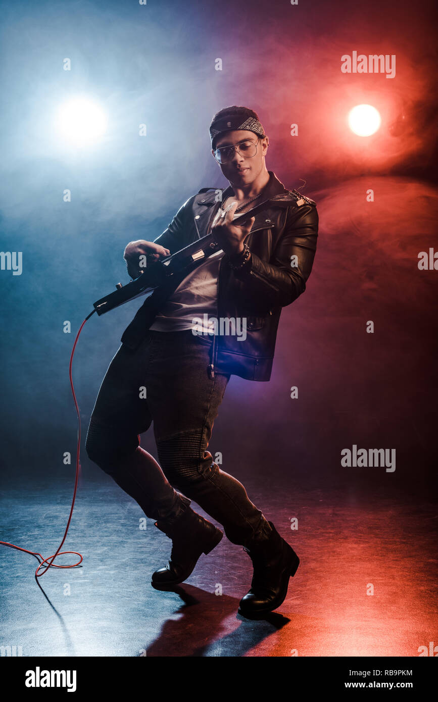 handsome stylish rocker in leather jacket performing on electric guitar ...