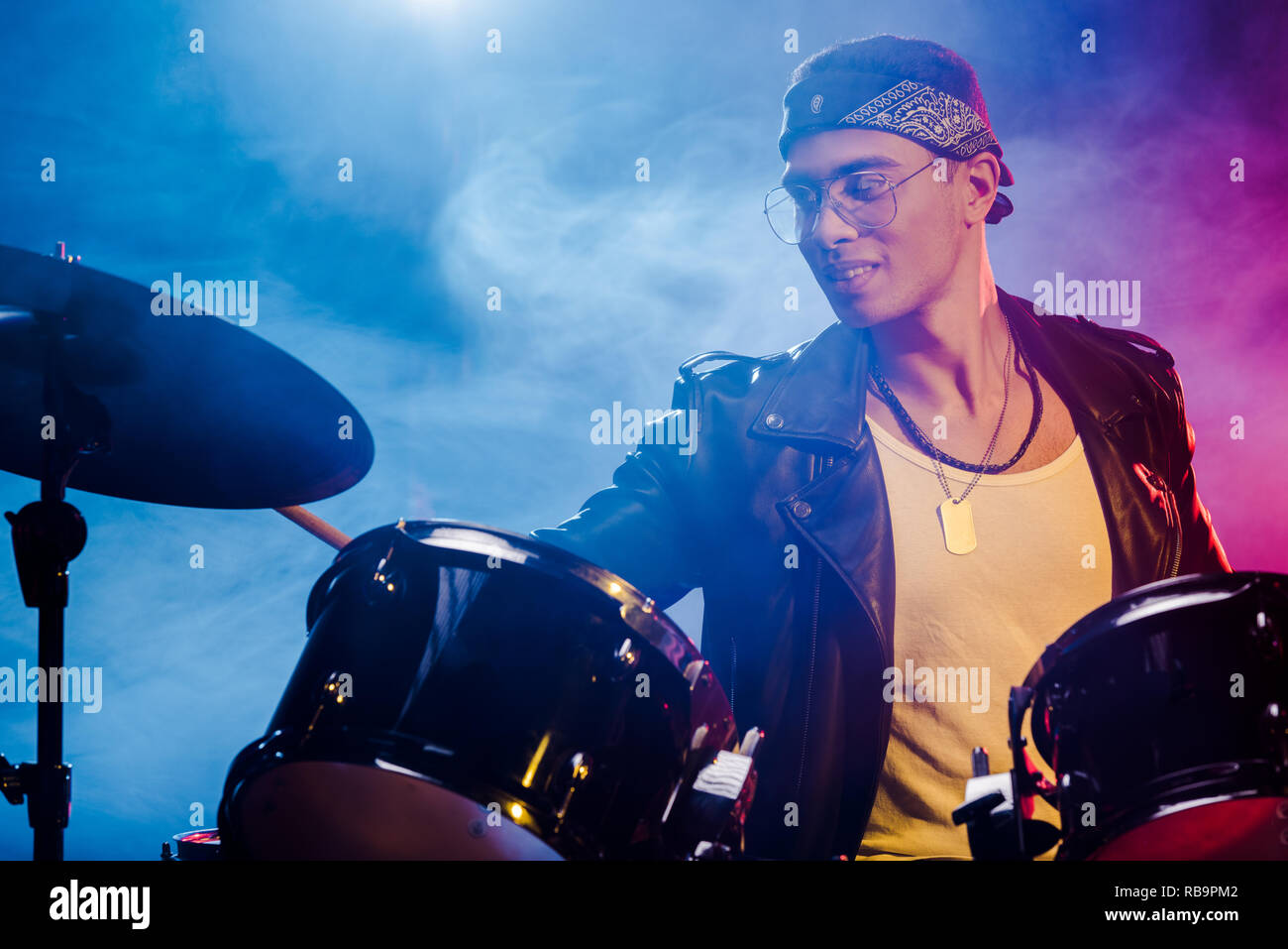 mixed race male musician playing drums during rock concert on stage ...