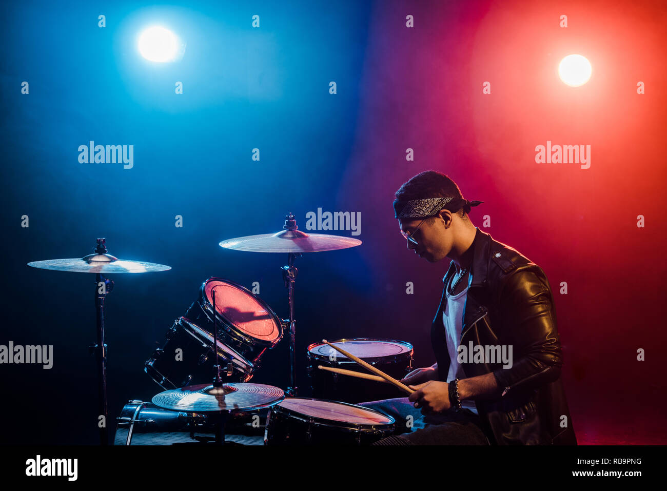 male musician in leather jacket playing drums during rock concert on ...