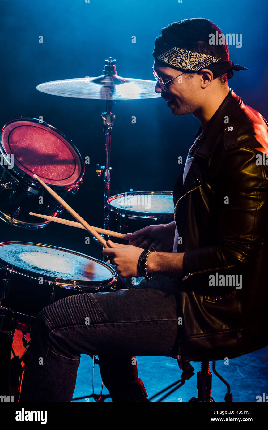 happy male musician in leather jacket playing drums during rock concert ...