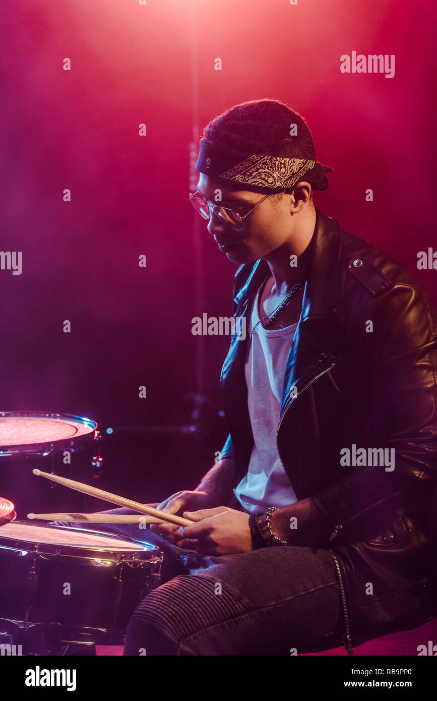male musician in leather jacket playing drums during rock concert on ...