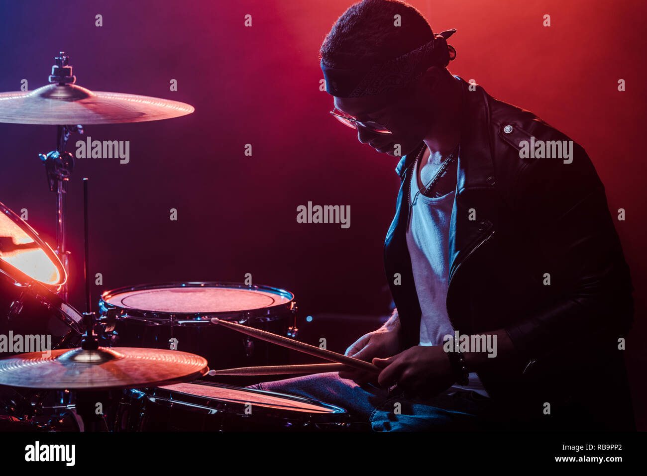 mixed race male musician in leather jacket playing drums during rock ...