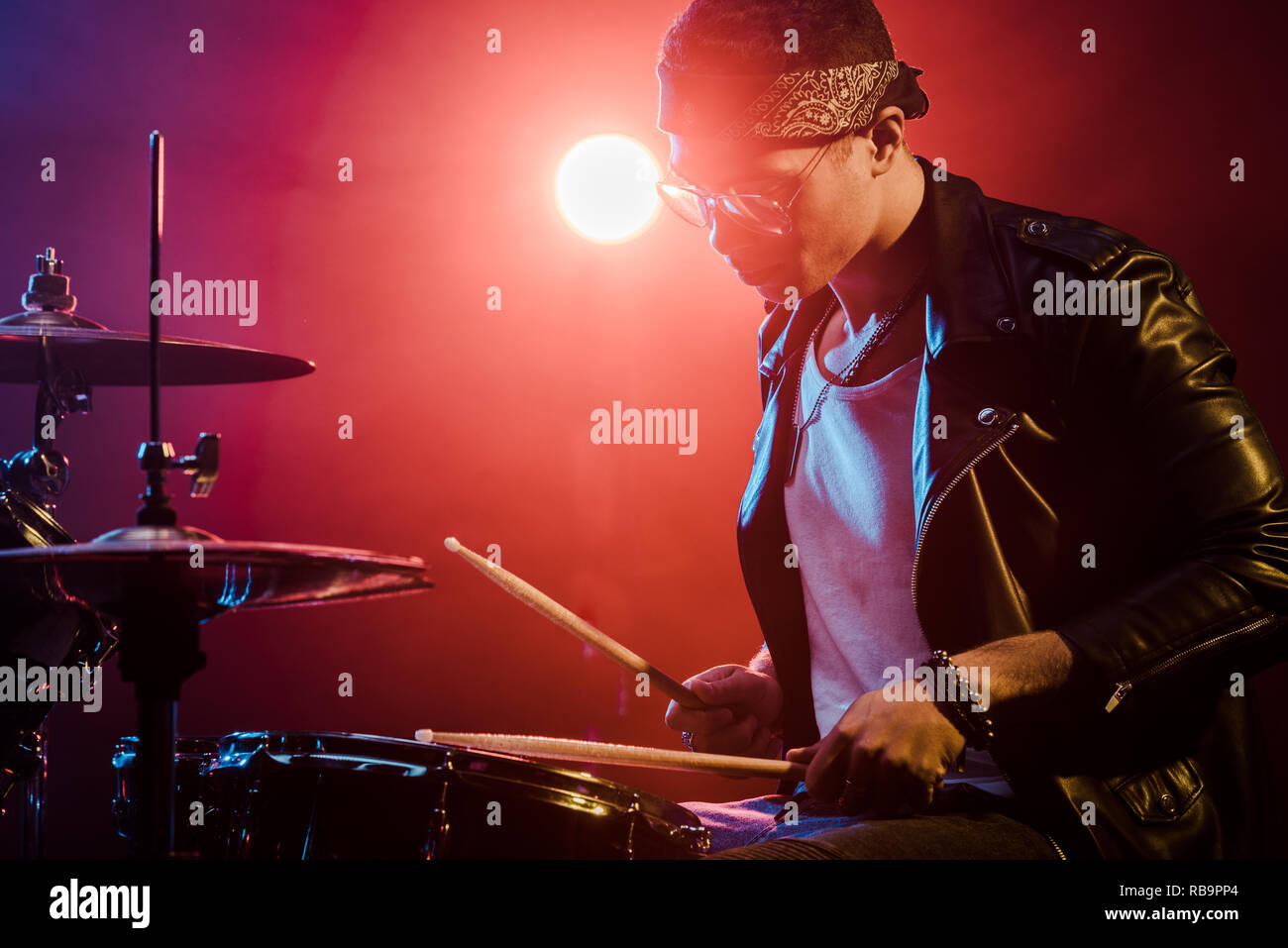 young male musician in leather jacket playing drums during rock concert ...